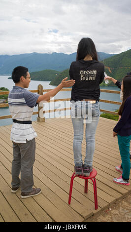A young woman standing on a stool facing her tall boyfriend Stock Photo ...