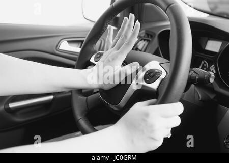 Honking the car horn in traffic jam, close up of male hand on vehicle steering wheel with ...