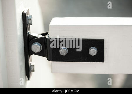 Closeup photo of metal clamp fixing two white wooden boards on bridge ...