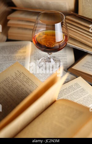 Glass of brandy standing on open books Stock Photo - Alamy
