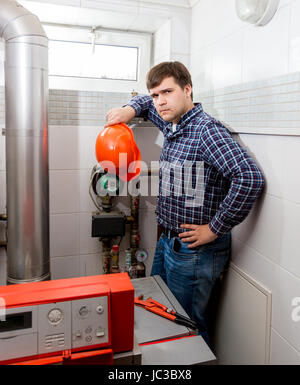 Professional confused plumber looking at complicated heating system ...
