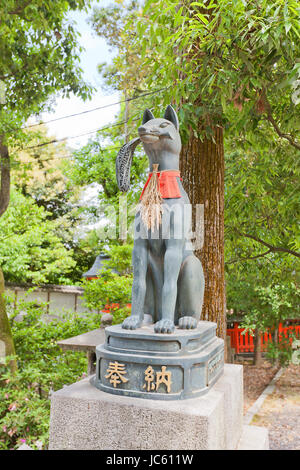 A statue of Inari Kitsune or fox goddess, wearing a red bib believed to ...