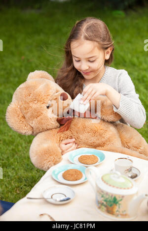 Tea-time with my Teddy. A little girl sitting outside having a tea ...