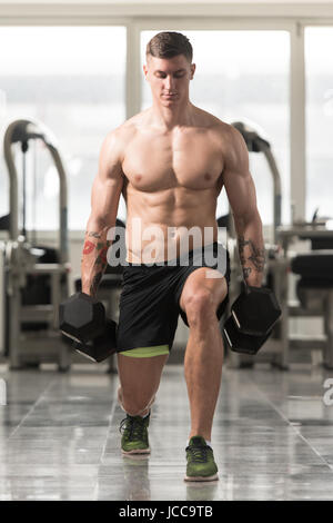 Young Man Working Out Legs With Dumbbells In A Gym - Squat Exercise ...