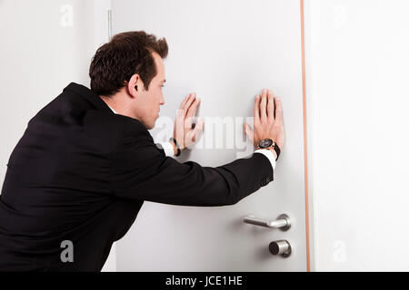 Businessman pushing the door to prevent people entering room Stock ...