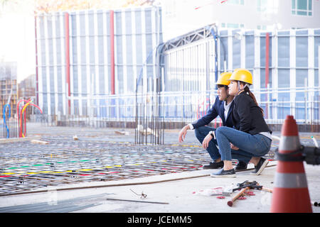 Two architects squatting at construction site Stock Photo - Alamy
