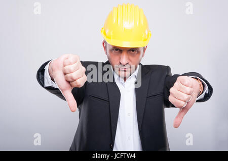 Foreman wearing hardhat making thumb up gesture and smiling on grey ...