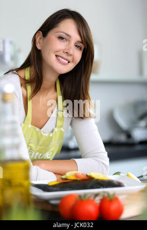 Smiling brunette woman cooking fish in home kitchen Stock Photo - Alamy