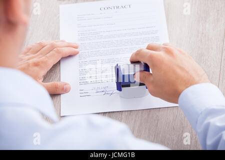 Cropped image of businessman stamping contract paper on table Stock ...
