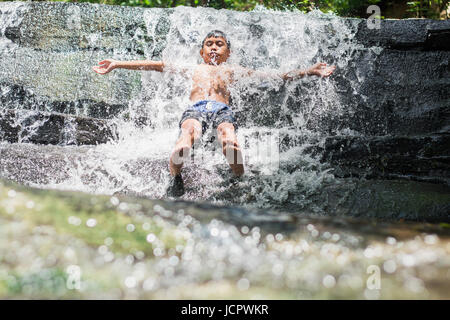 Boy playing waterfall Flowing from the jungle Stock Photo - Alamy