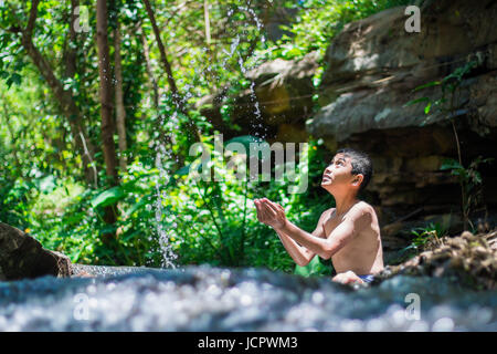 Boy playing waterfall Flowing from the jungle Stock Photo - Alamy