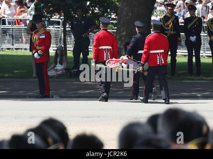 A fainting Guardsman is carried off the parade ground as The Queen ...