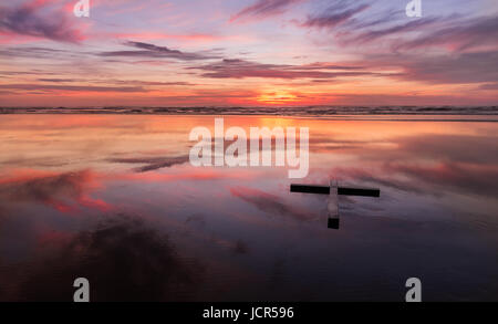 Cross lay down on a flat reflection beach at sunset Stock Photo - Alamy