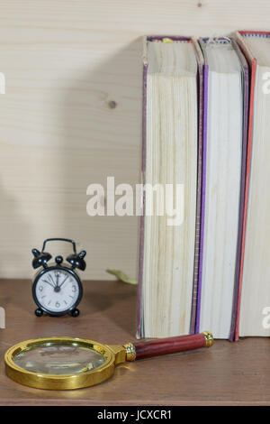 Old blue book with a magnifying glass and pen on top, on a wooden desk ...