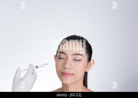 Doctor's hand making a botox injection in girl's face. young asian ...