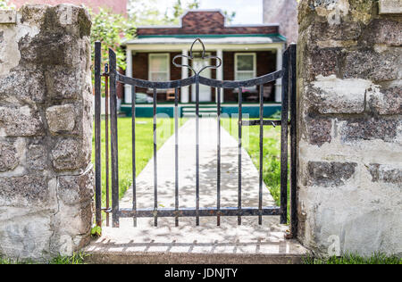 A metal gate leading in front of steps leading to the front door of an ...