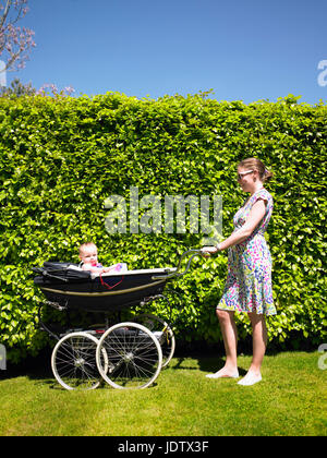 A mother with pushing pram and baby, summer park Stock Photo - Alamy