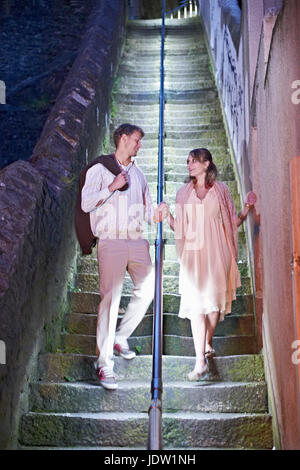 Two people talking on steps leading to wooden summer house next to red ...