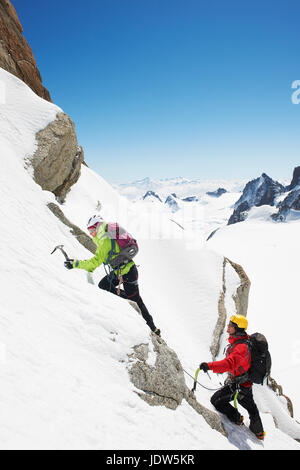 Two people climbing mountain Stock Photo - Alamy