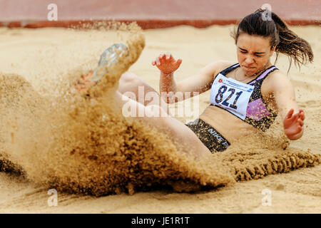 Young athlete landing in the sand pit during the long jump Stock Photo ...
