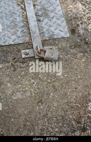 Locked padlock blocking access to manhole cover. Metaphor locked in ...