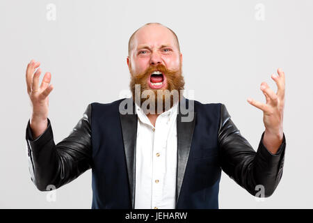 Brutal screaming man with ginger beard in gray jacket on empty ...