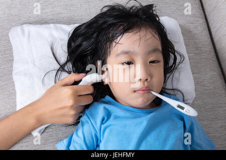 Asian Chinese little girl getting ear measurement for fever temperature ...