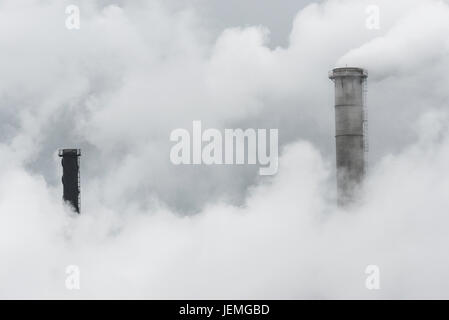Low angle shot of the factory chimneys with white smoke on the ...