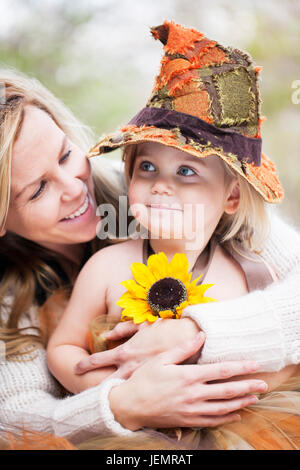 Front view of blonde mother wearing christmas hat and daughter sitting ...