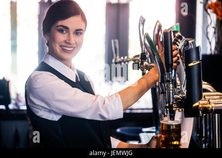 smiling young barmaid serving a pint in a traditional british pub the ...