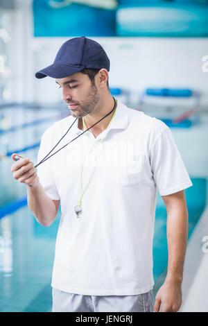 handsome swim trainer with stopwatch standing at competition swimming ...