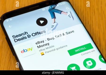 Smartphone with eBay logo on the screen, shopping cart and blurred ...