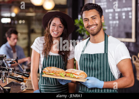 Smiling baristas holding bread and sandwiches Stock Photo - Alamy