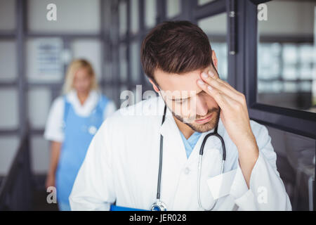 Male doctor suffering from a headache and fatigue holding his temples ...