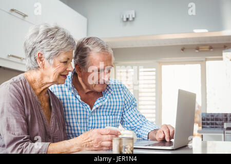 Senior couple with pills using laptop Stock Photo - Alamy