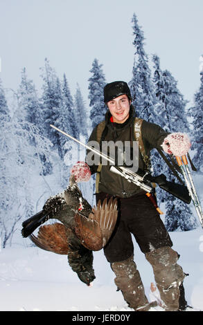 Portrait of a young man standing with a bird of prey perched on his ...