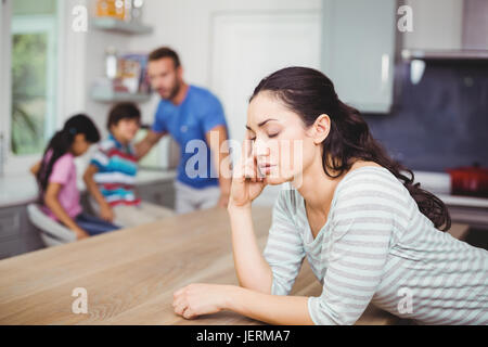 Upset mother is sitting at the table and her family is sympathying with ...