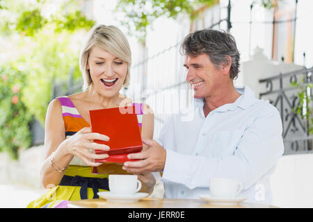 Man gifting woman at cafe Stock Photo - Alamy