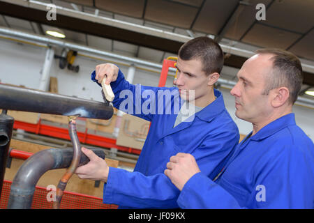 tradesman training two apprentices Stock Photo - Alamy