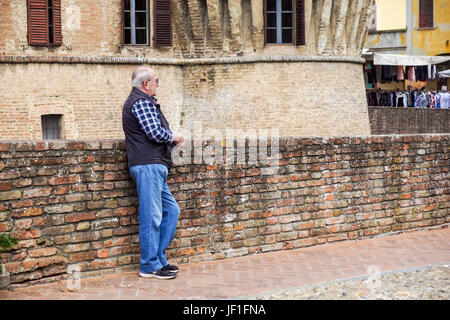 PARMA, ITALY - APRIL 2017 : an older man waits Near the brick wall ...