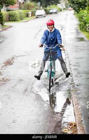 Woman riding bicycle through puddle Stock Photo - Alamy