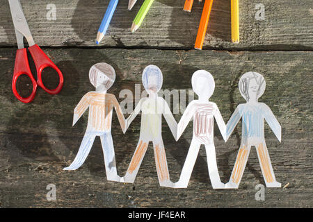 Teamwork concept. Paper figures of people holding hands on white table ...