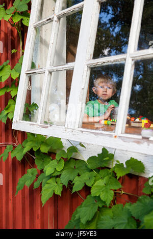 Boy climbing out of window Stock Photo - Alamy