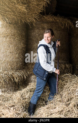 Woman with hay and pitchfork working on farm feeding sheep Stock Photo ...