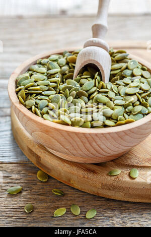Pumpkin seeds, peeled, green. Vegetarian food. On a white wooden ...