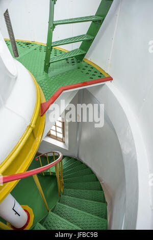 Steps up to a circular lighthouse with yellow flowers in the foreground ...