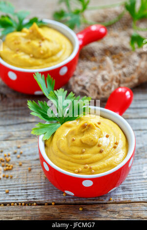 Yellow mustard in white ceramic bowl with swiss cheese slices on wooden ...