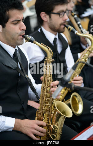 Musicians playing wind instruments while sitting next to images; Music ...