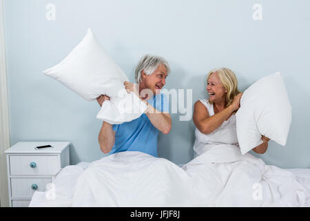 Senior man playing pillow fight with grandson in living room Stock ...