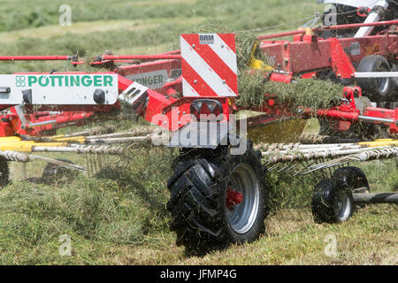 Tractor raking grass for silage harvesting. Agriculture farm machinery ...